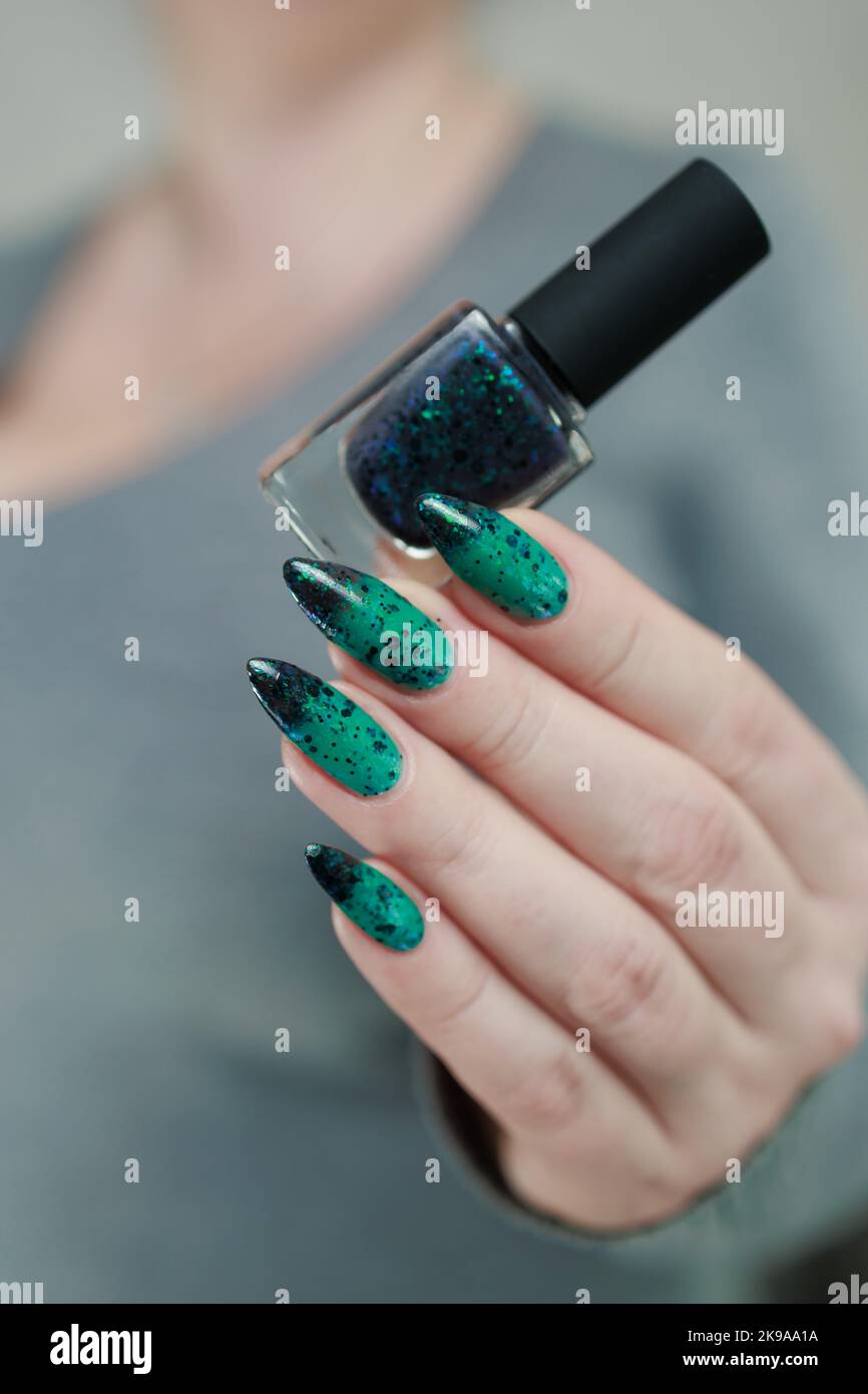 Female hand with long nails and green-black thermo french nail polish ...