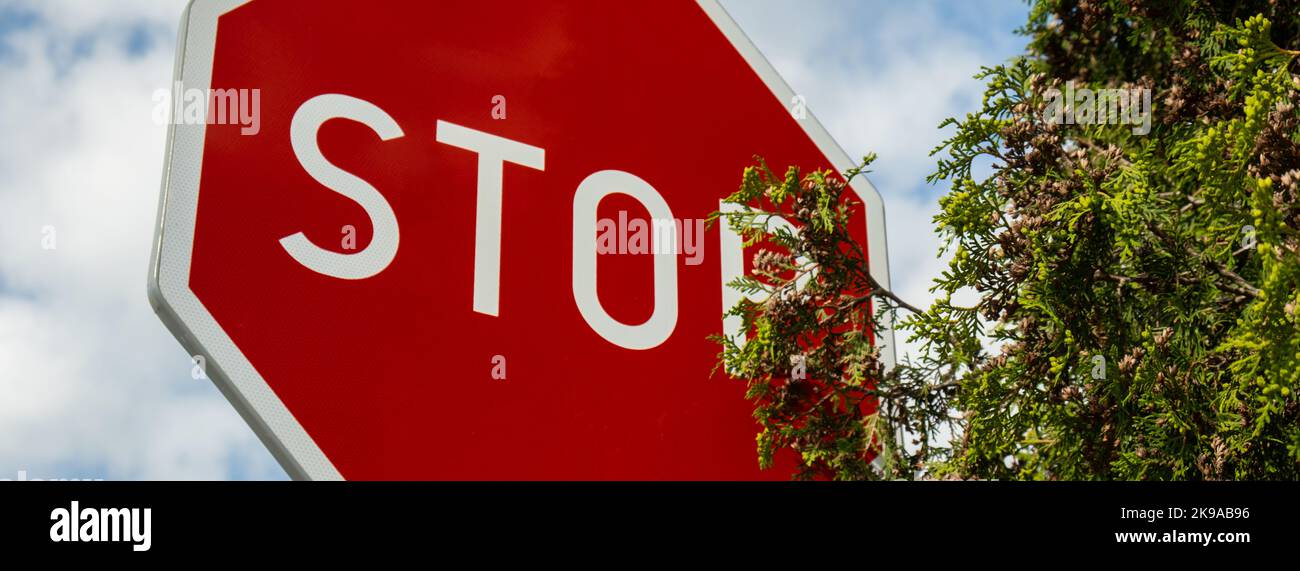Red stop sign on metal pole on street. Road attention sign on cloudy ...