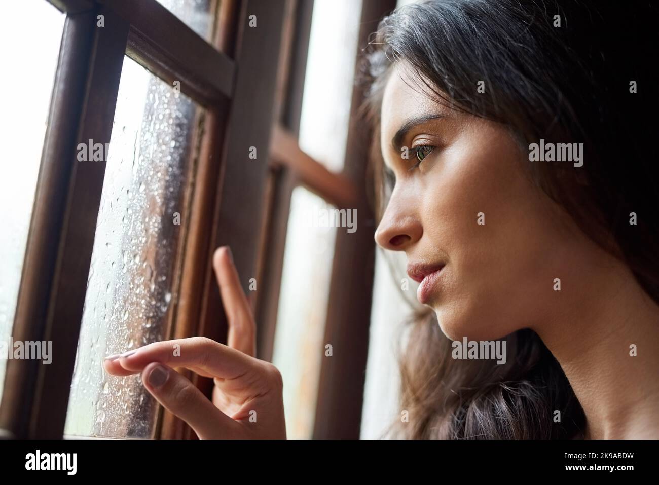 This rain better not ruin my day. an attractive young woman looking out ...