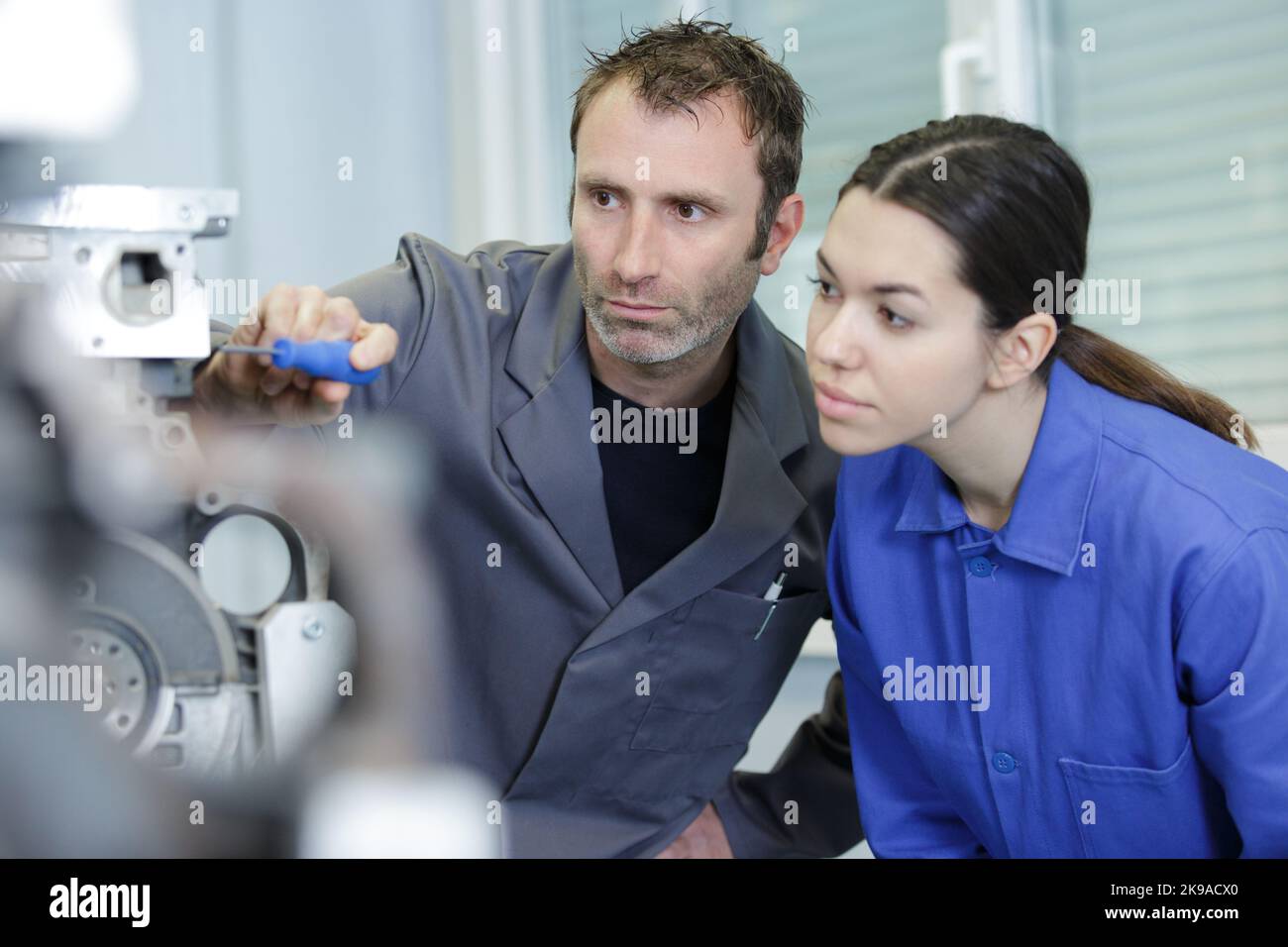 engineer showing apprentice talking about machine Stock Photo - Alamy