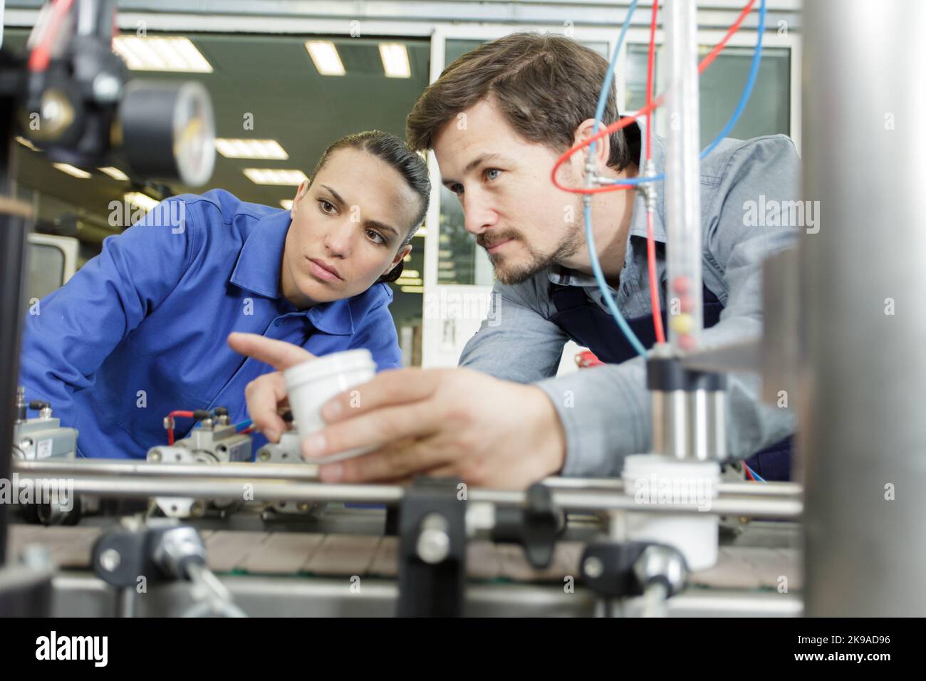 engineer training female apprentice on production machine Stock Photo ...