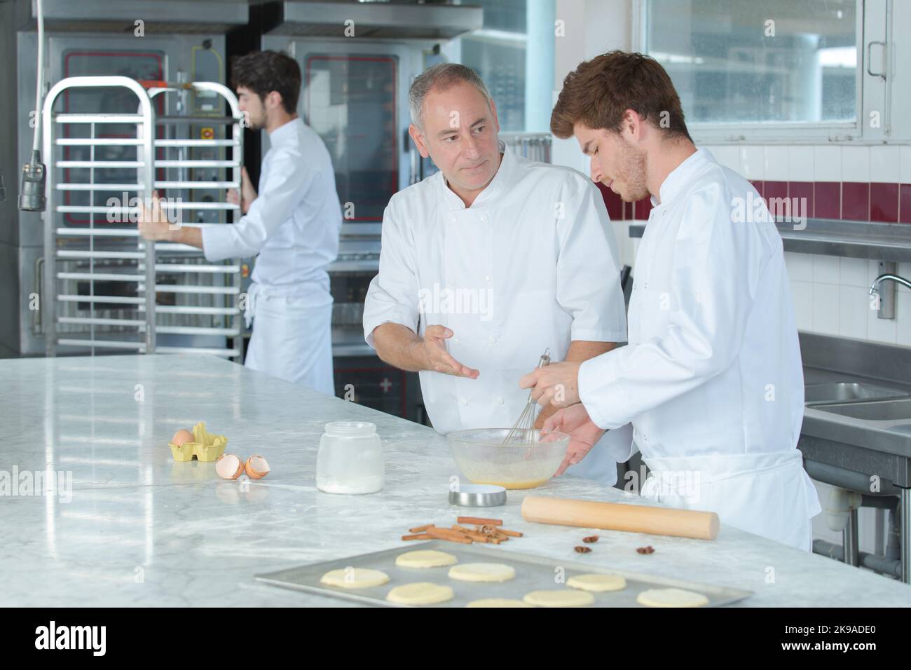 baker instructing apprentice how to knead dough properly Stock Photo ...