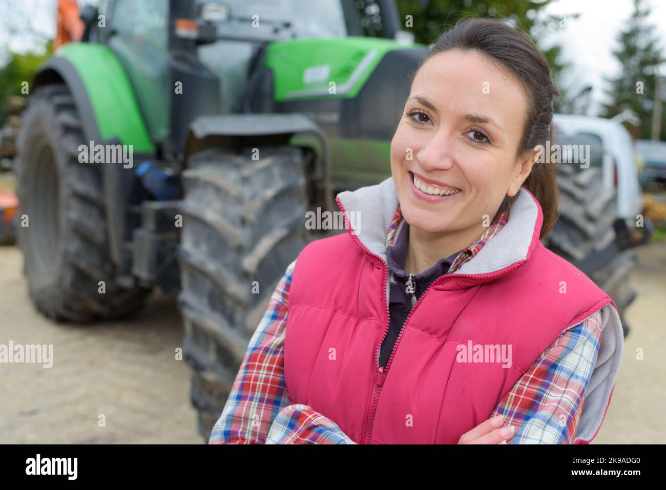 pretty brunette farmer posing in front of her tractor Stock Photo - Alamy
