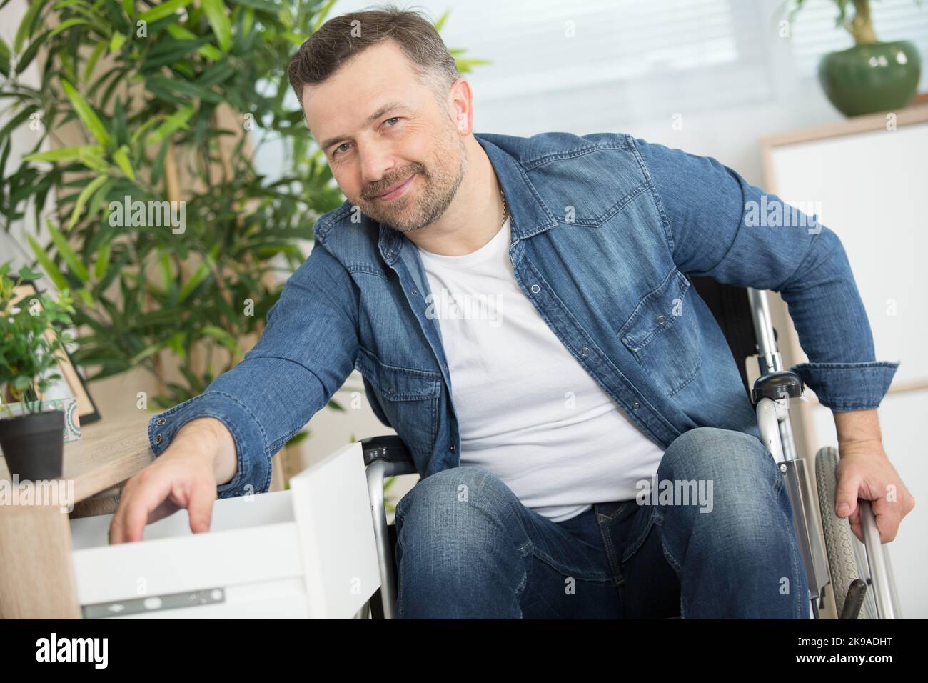 man in wheelchair reaching into a drawer Stock Photo - Alamy