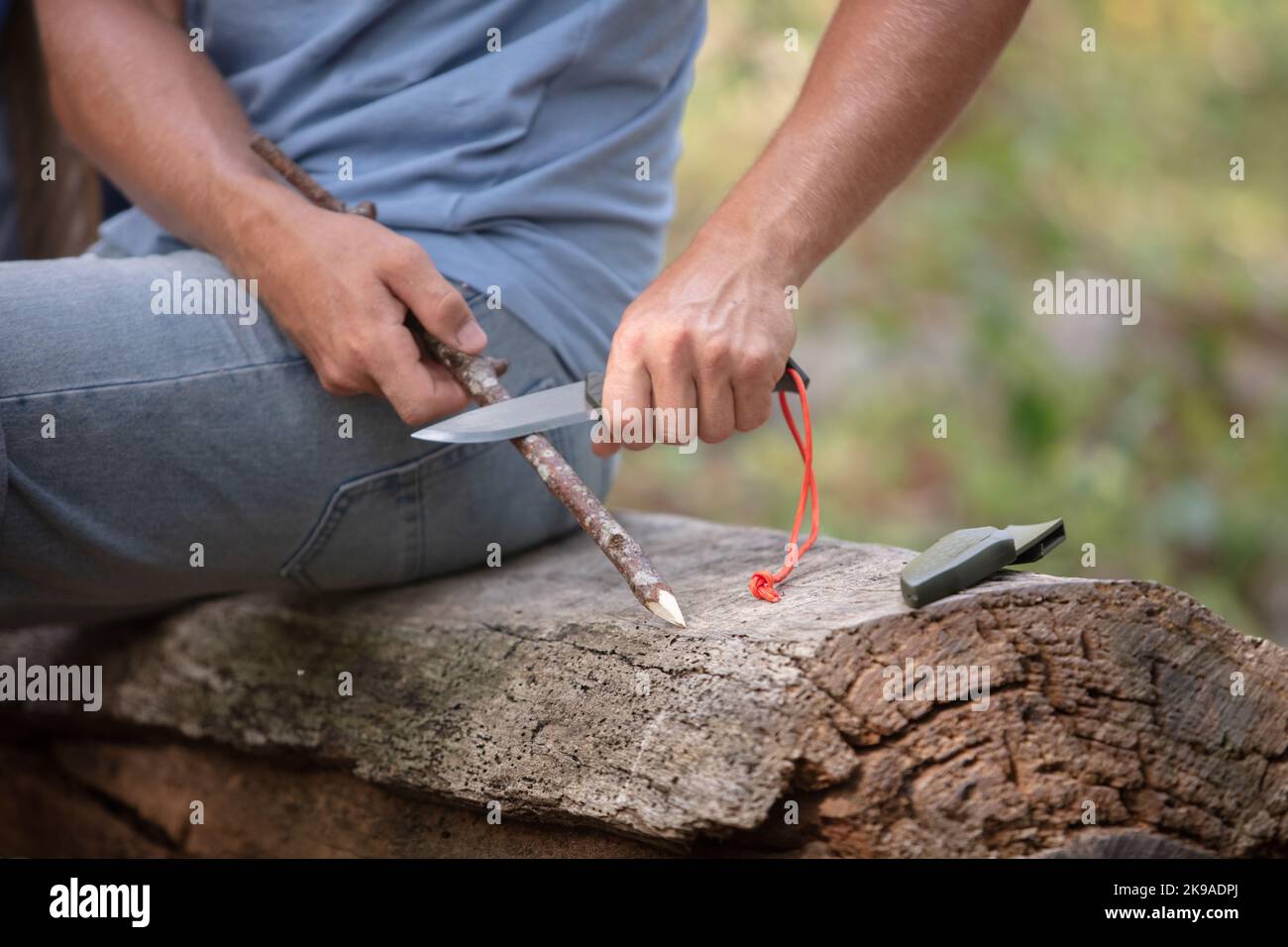 man uses a knife to whittle a stick out hiking Stock Photo - Alamy