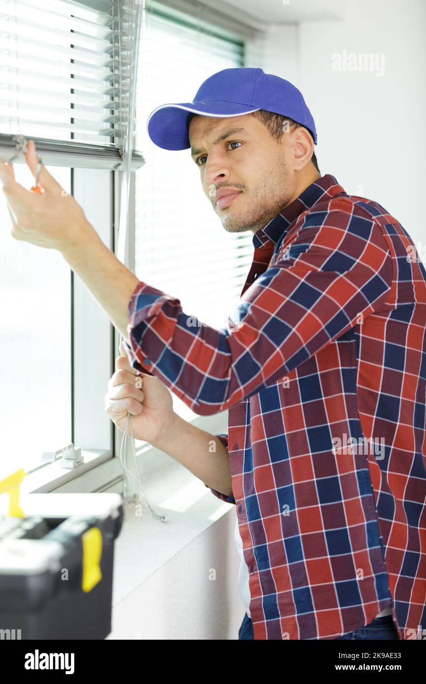 handyman installing slatted window blinds Stock Photo - Alamy