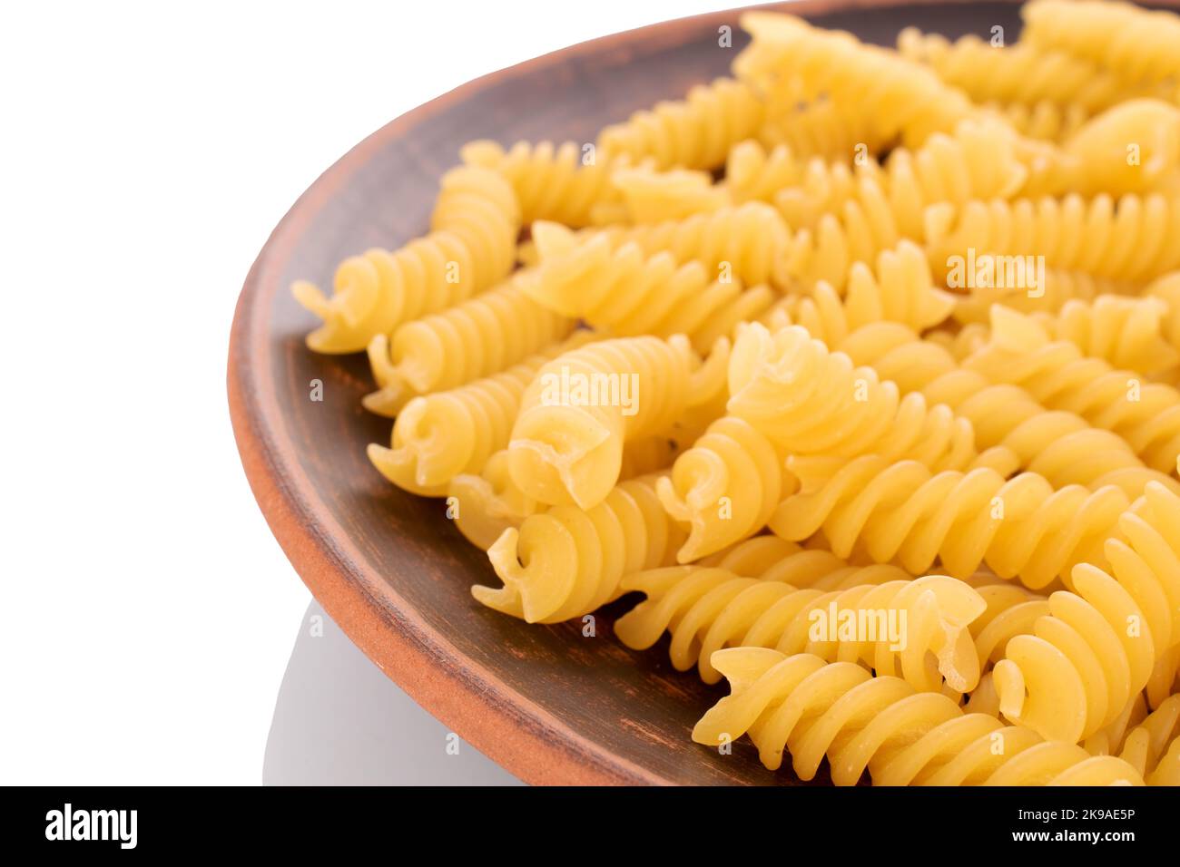 Durum wheat pasta on a clay plate, macro, isolated on white background ...