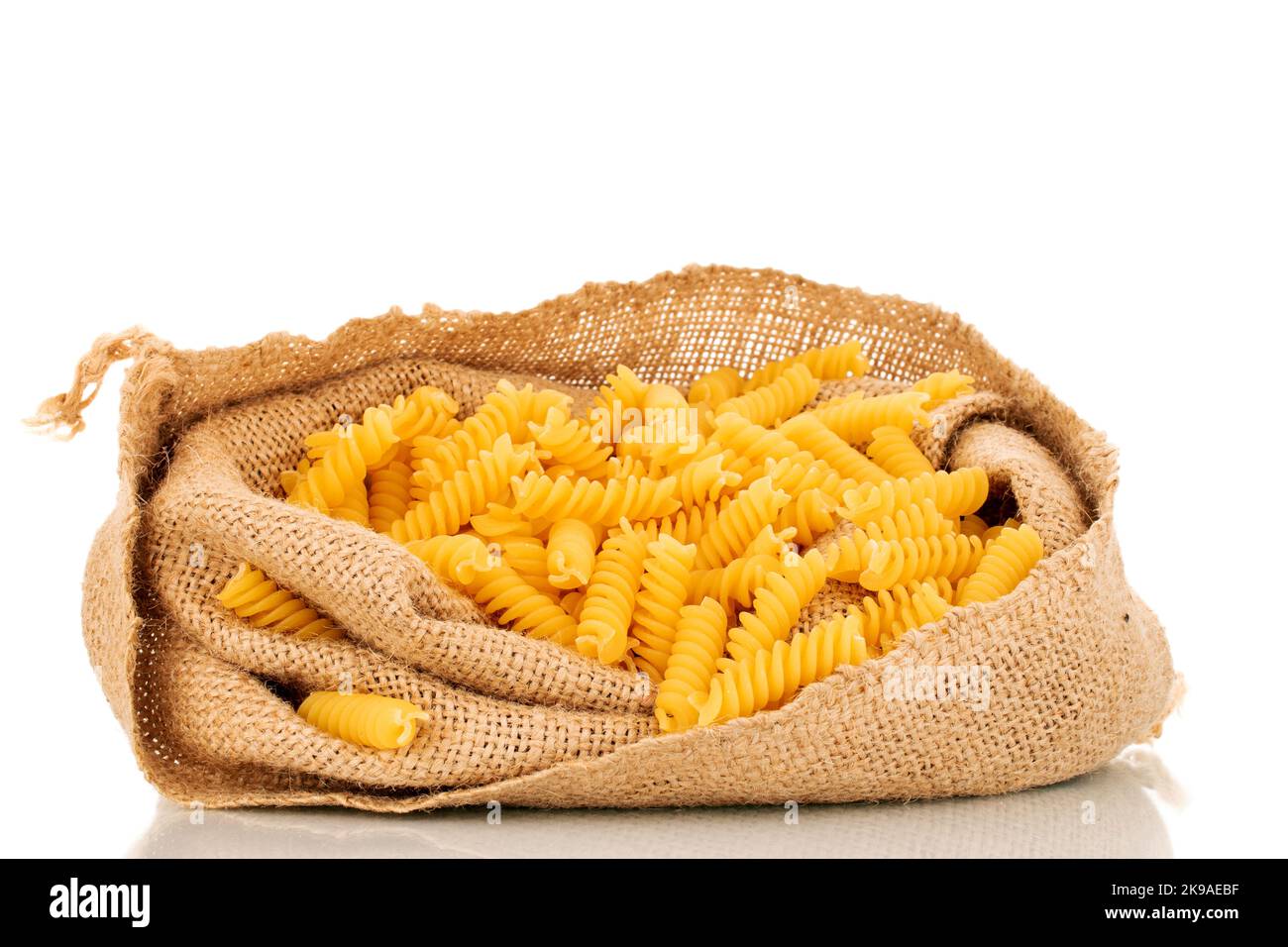 Durum wheat pasta in a jute bag, macro, isolated on white background ...