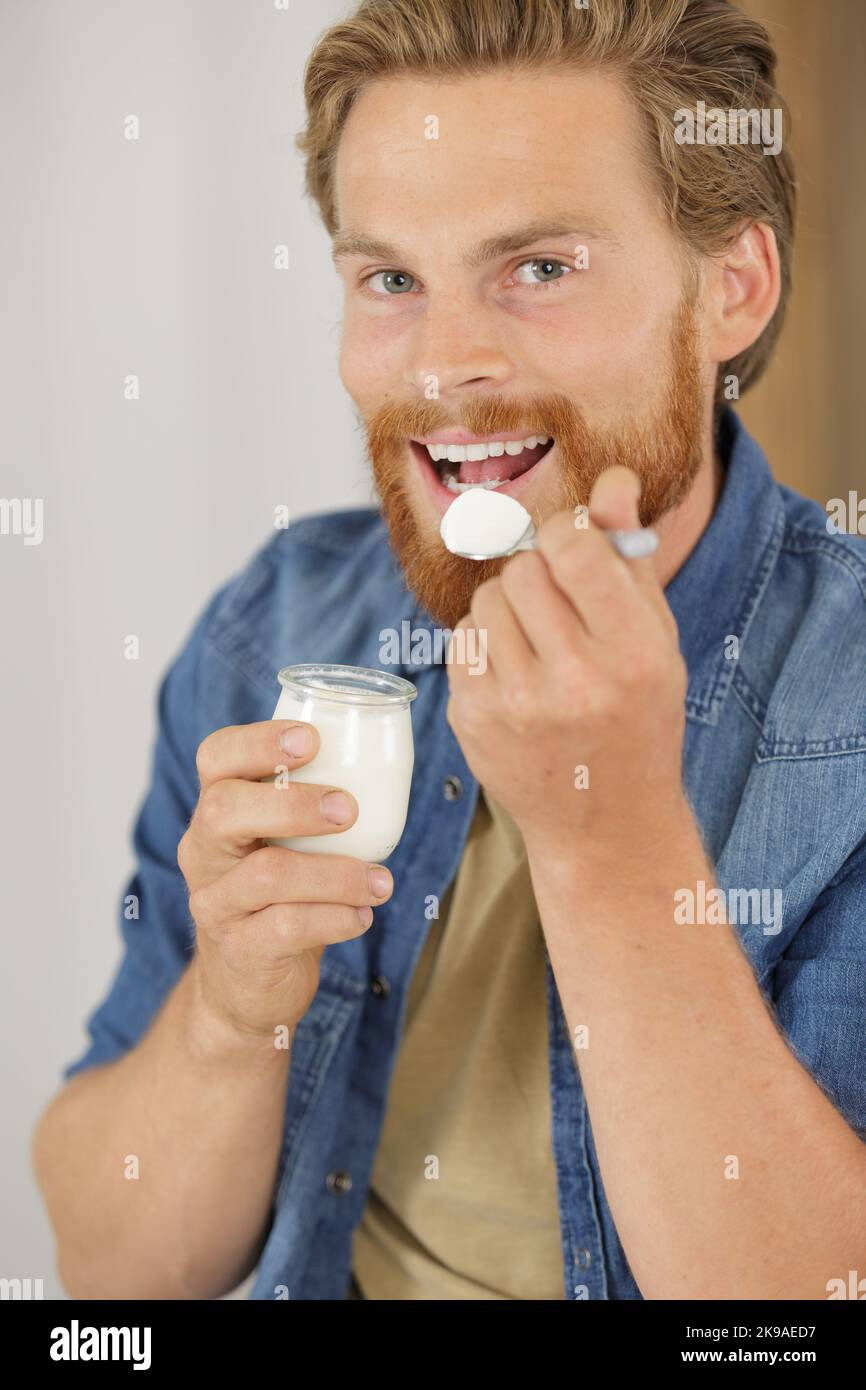 Young man eating yoghurt hi-res stock photography and images - Alamy
