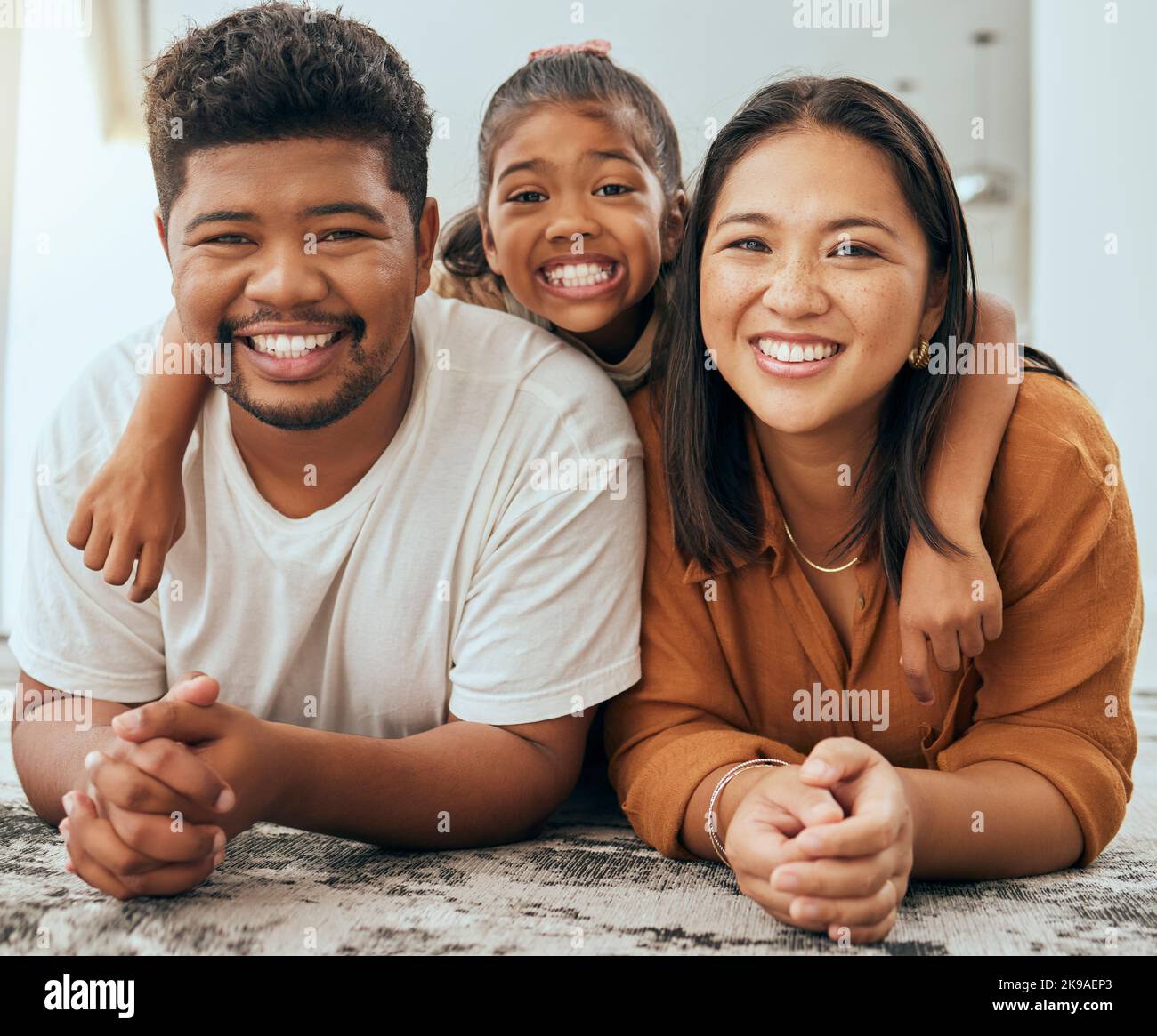 Portrait, girl and parents on the floor of their living room with hug ...