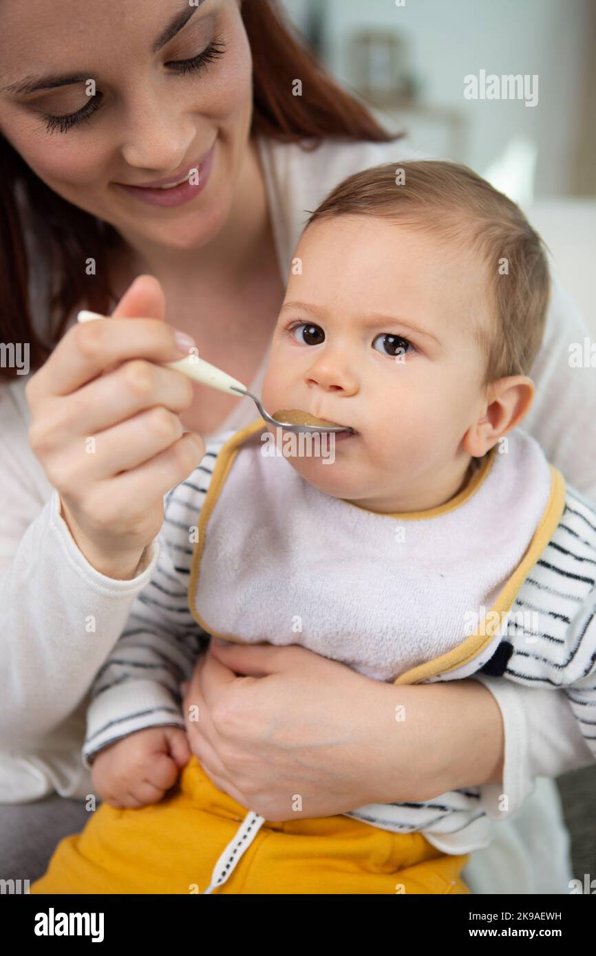 mother giving fruit puree to her infant child Stock Photo - Alamy