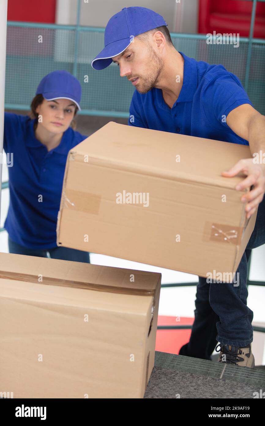 movers in blue uniform carrying cardboard boxes on staircase Stock ...