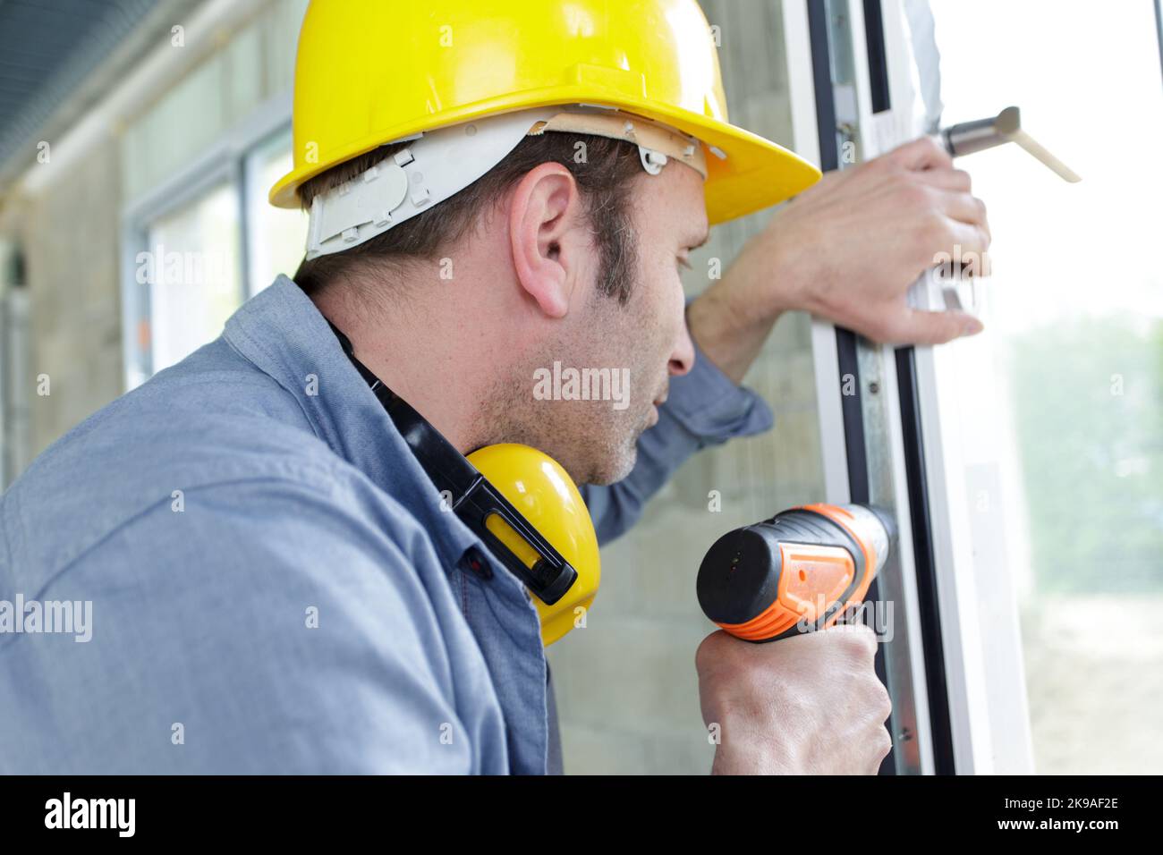man drilling a hole in a window frame Stock Photo - Alamy