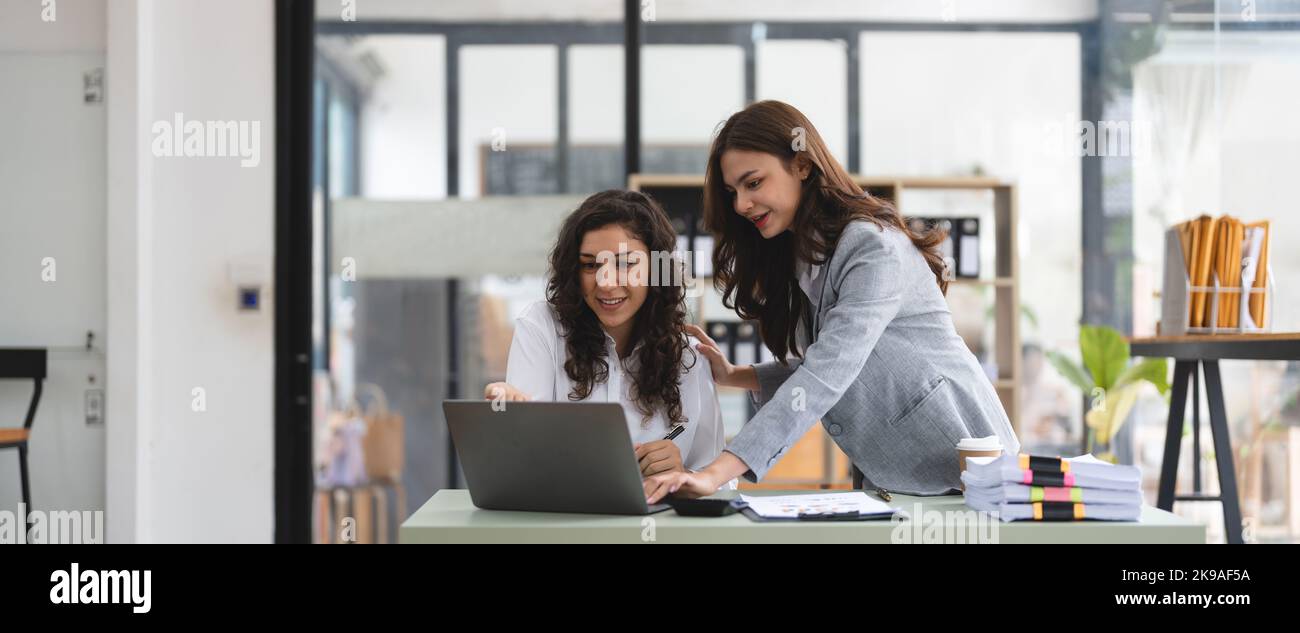 Two smart multiethnic business people working together with laptop ...