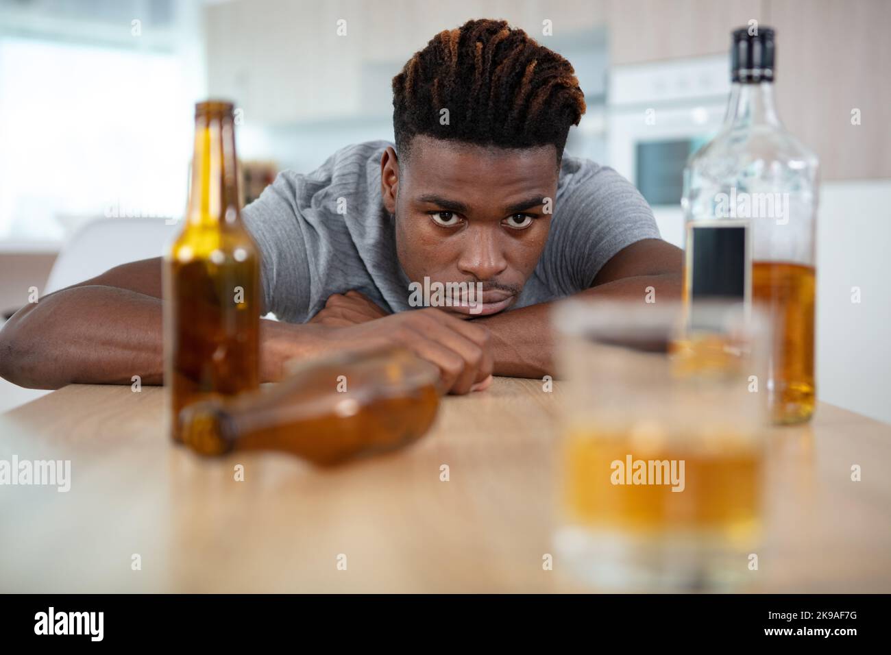 man staring across table at glass of alcohol Stock Photo - Alamy
