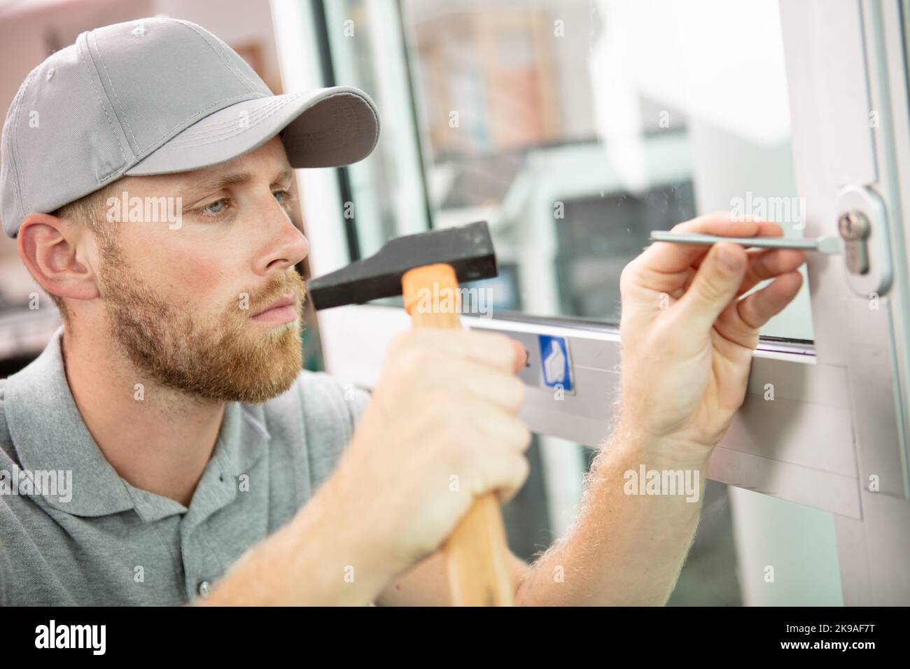 locksmith fitting door lock using a hammer Stock Photo - Alamy