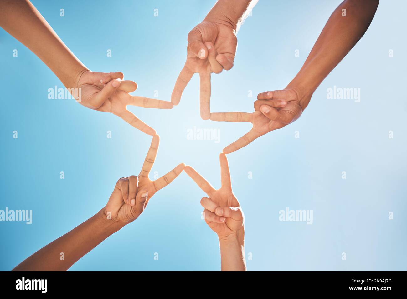 Hands, star and teamwork with friends in a huddle on a clear blue sky ...