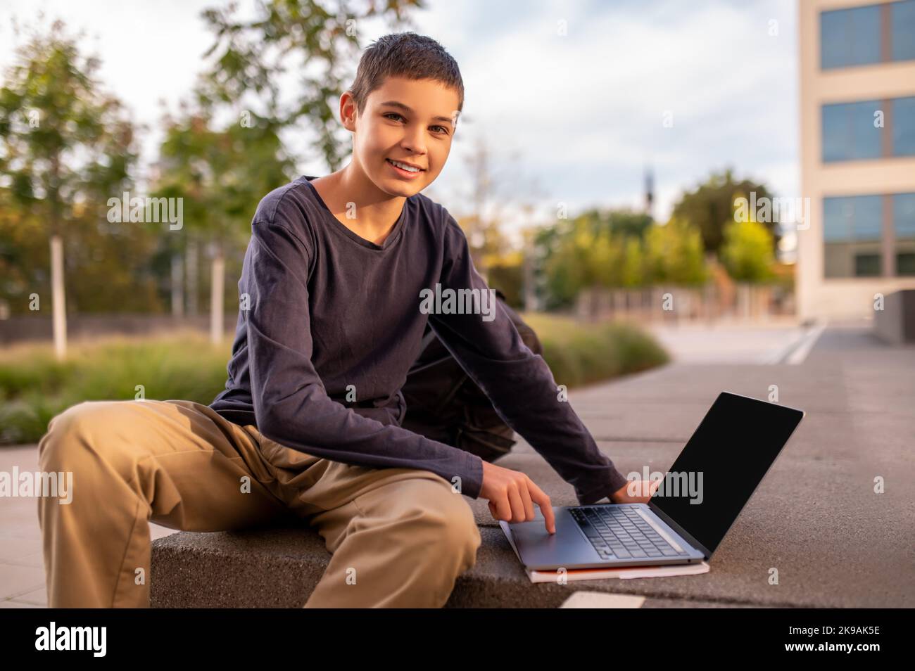 Pleased teenager using his portable computer outdoors Stock Photo - Alamy