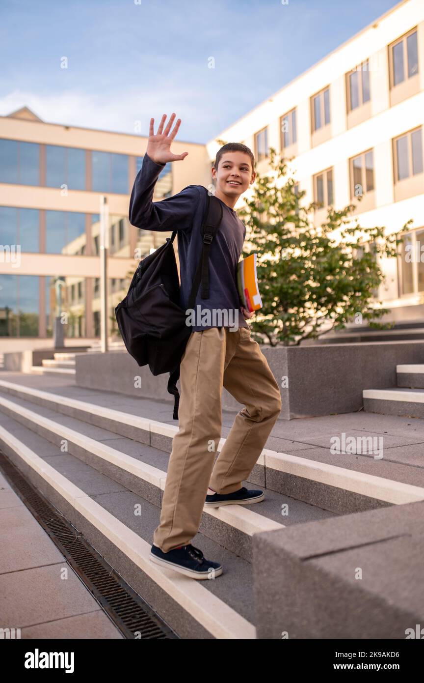 Smiling teenage boy greeting someone in the distance Stock Photo - Alamy