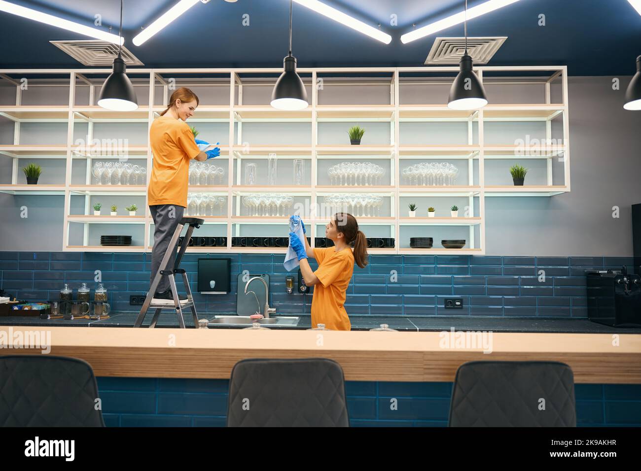Female employees communicate during general cleaning process in kitchen ...