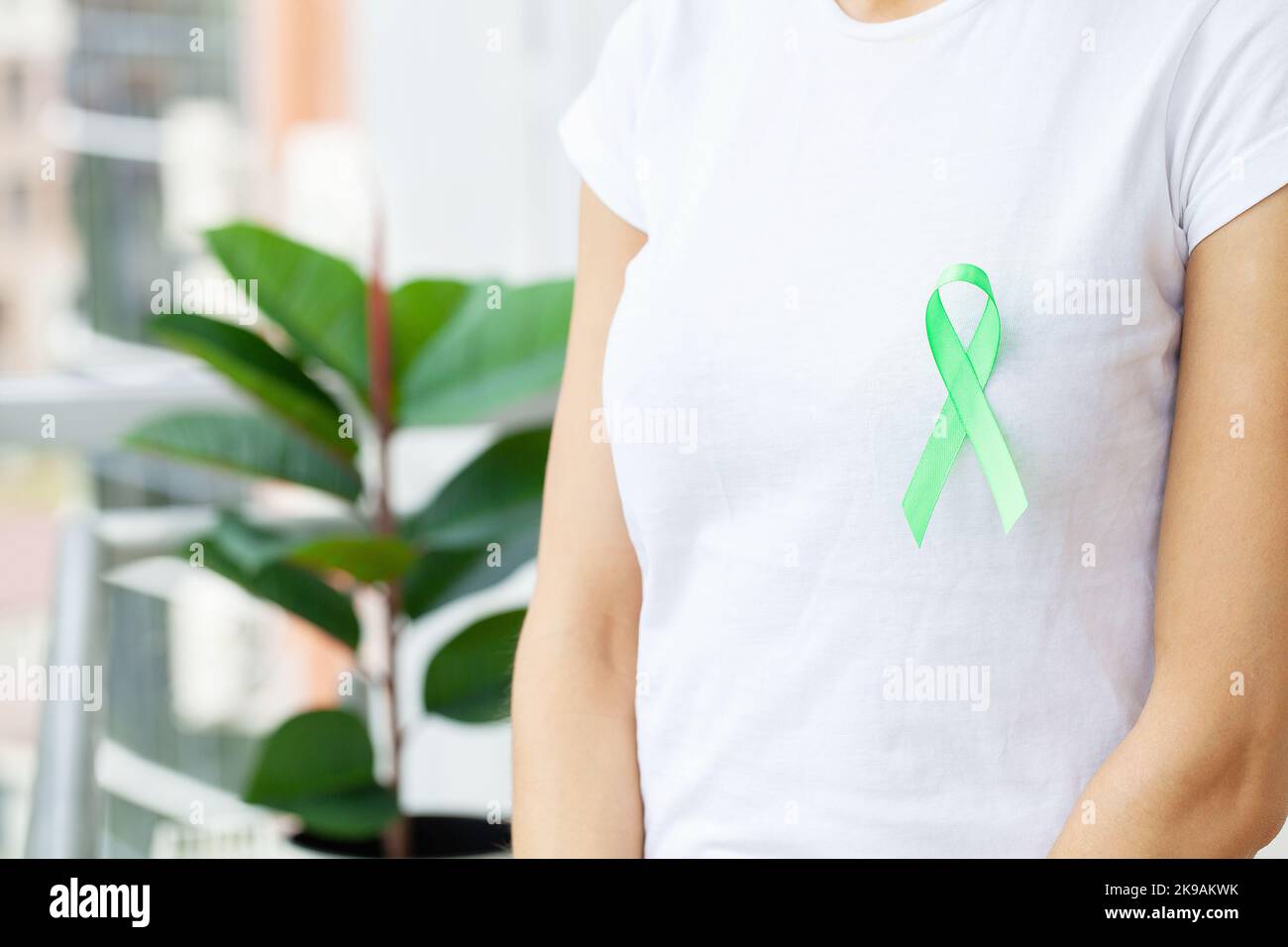Green ribbon in hand as a symbol to awareness Lymphoma cancer Stock ...