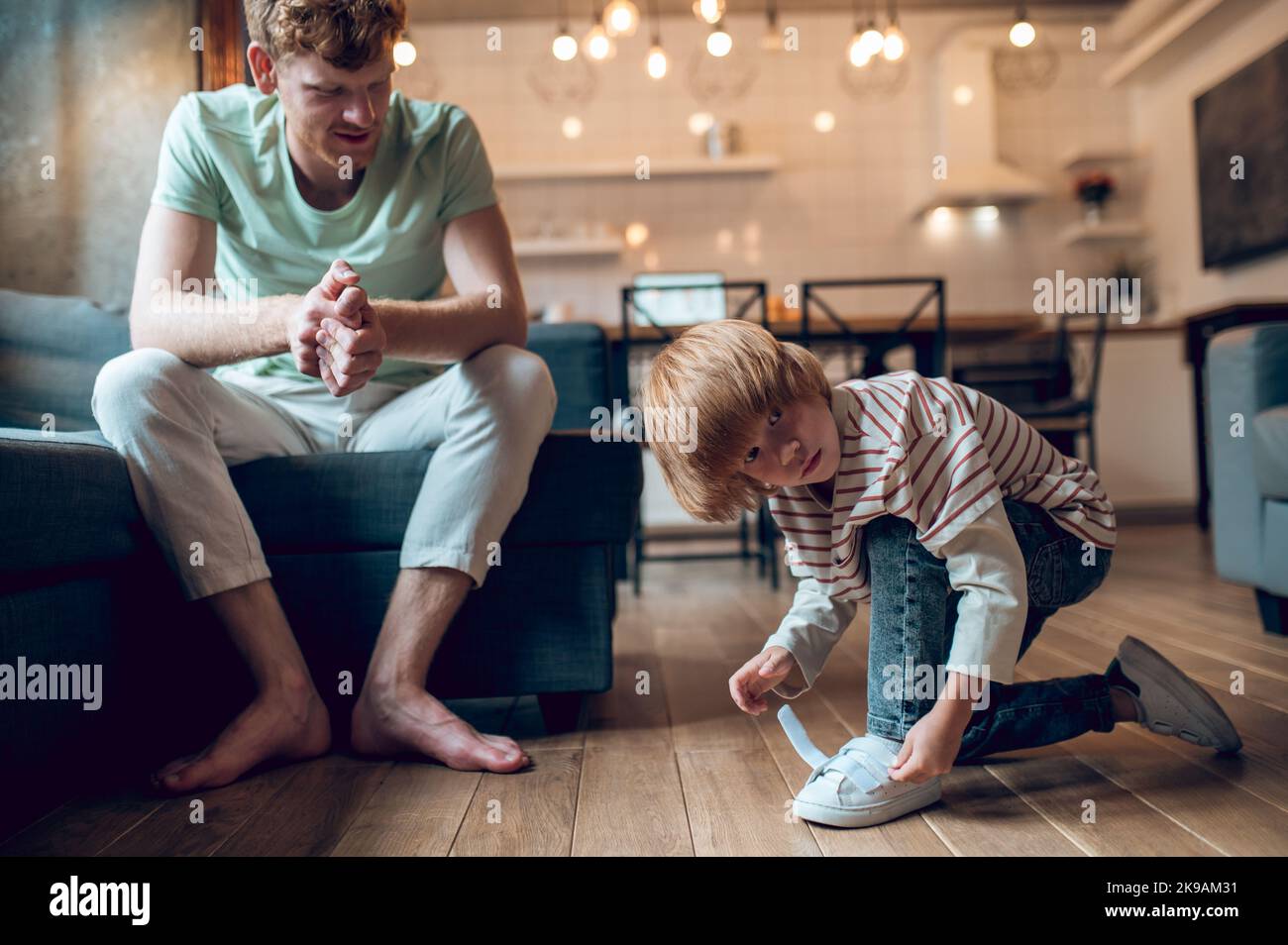 Little boy looking busy while getting on his shoes Stock Photo - Alamy