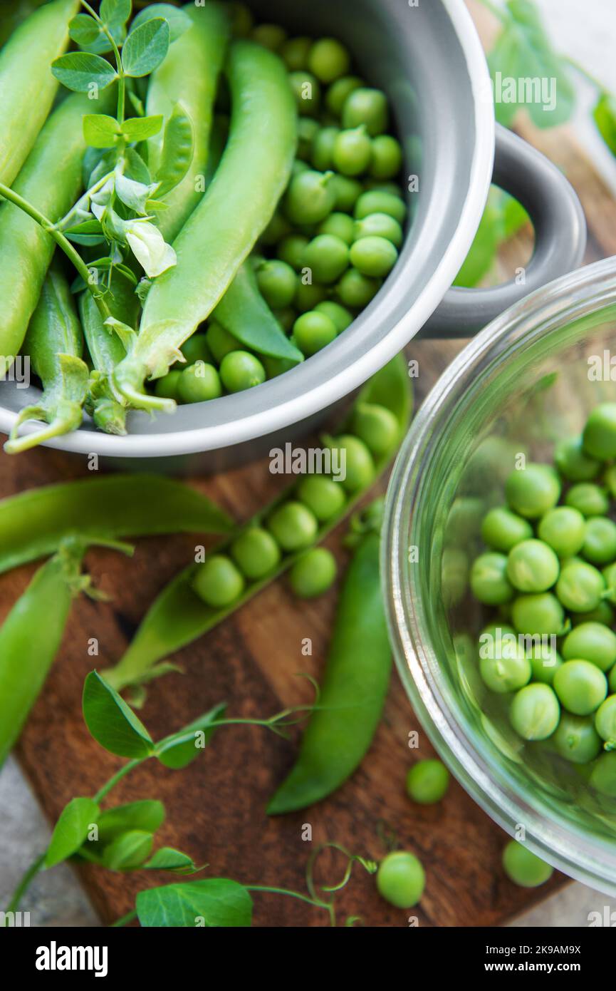 Bowl with young fresh juicy pods of green peas on a wooden background ...
