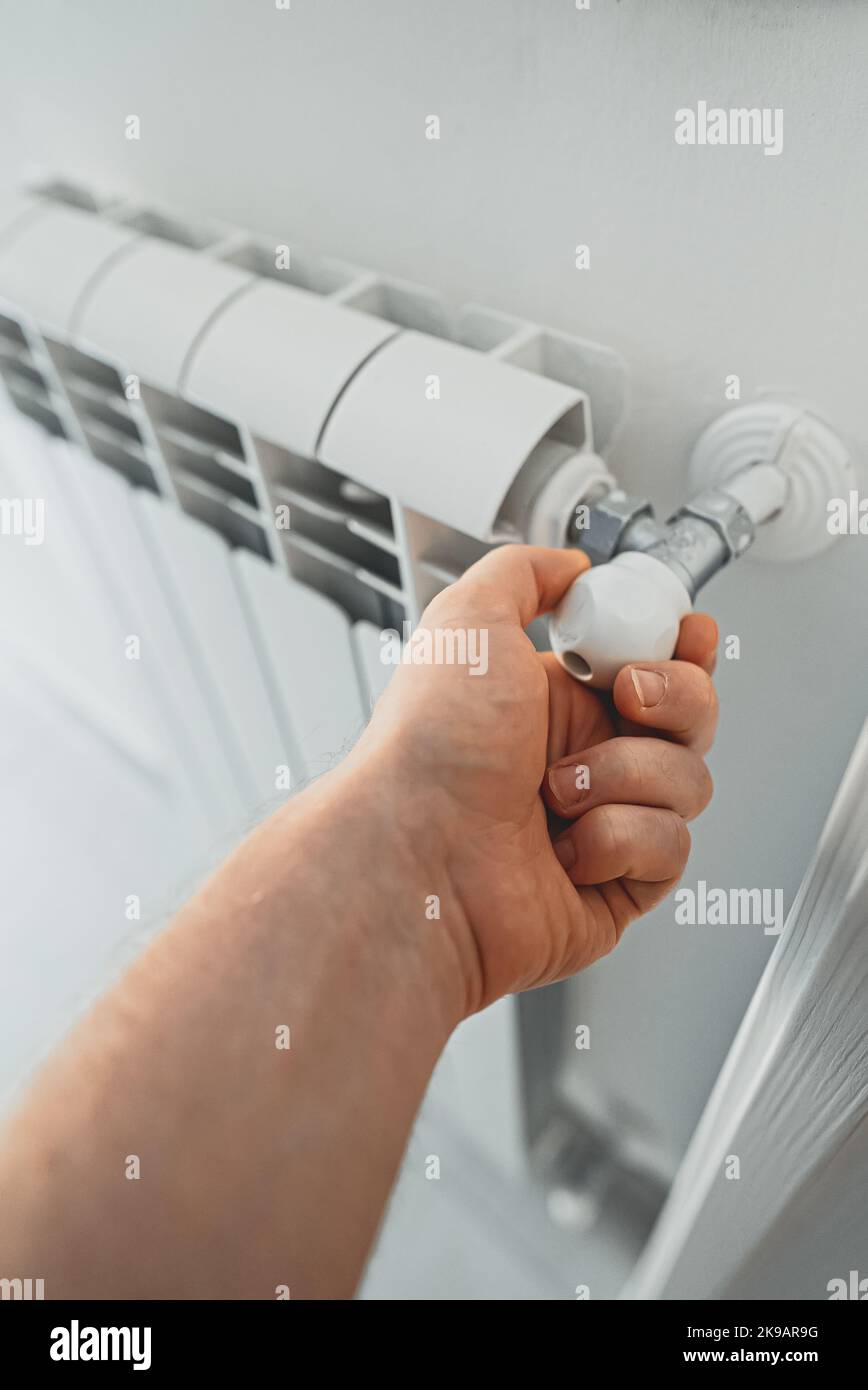 Male hand adjusting thermostat to turn on the radiator heater at home ...