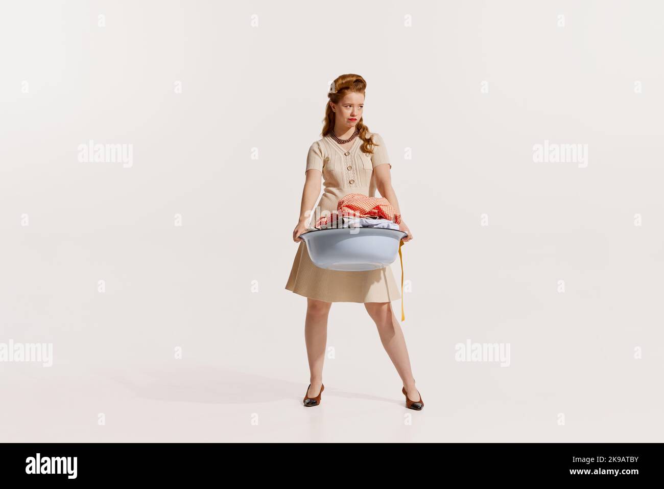 Portrait of young elegant woman doing washing, carrying bowl with ...