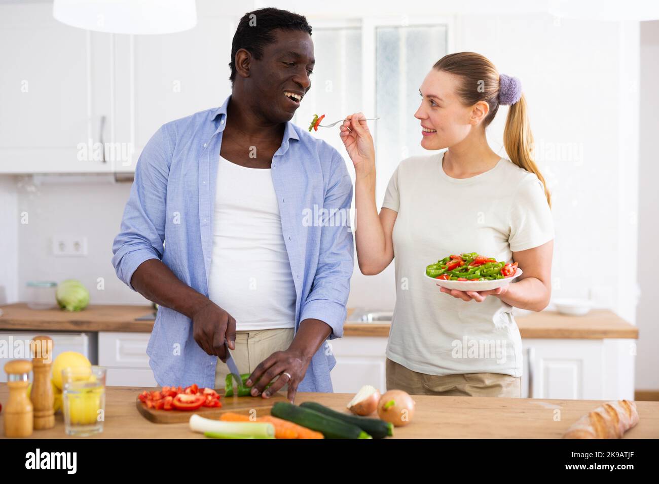 Happy biracial family couple cooking healthy vegetable dinner together ...