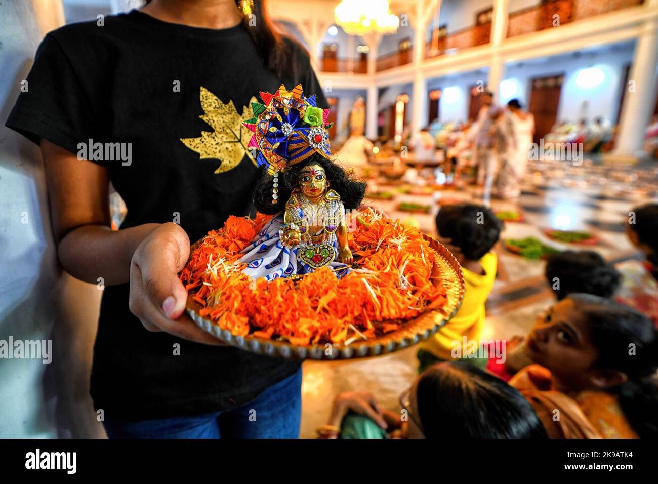 A devotee seen holding an idol of Lord Krishna on the occasion of Annakut or Goverdhan puja at ...