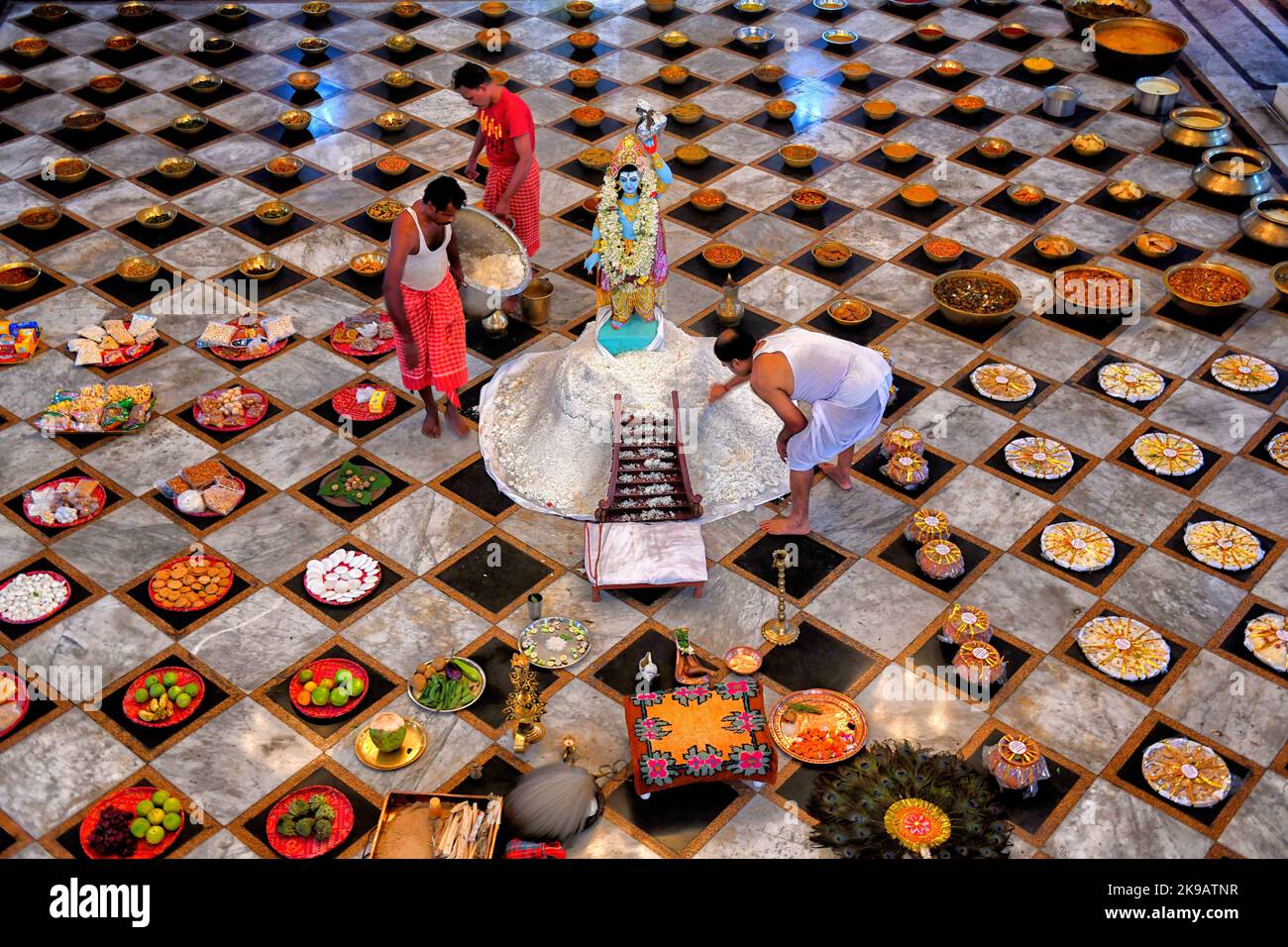 A Priest and some devotees seen preparing for Annakut or Goverdhan puja at Naba Brindaban temple ...