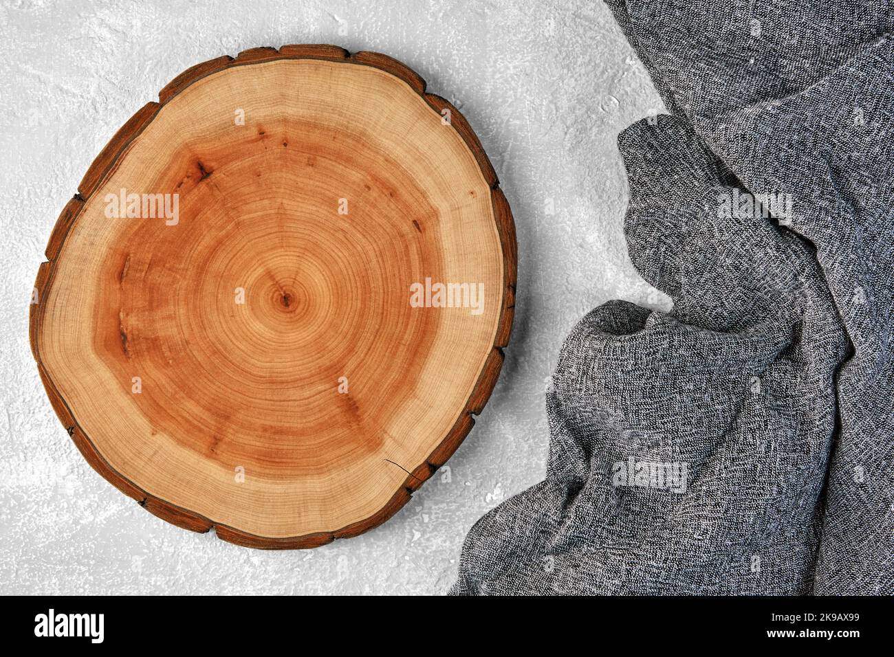 Wooden cutting board or dish coaster and gray kitchen towel on a light ...