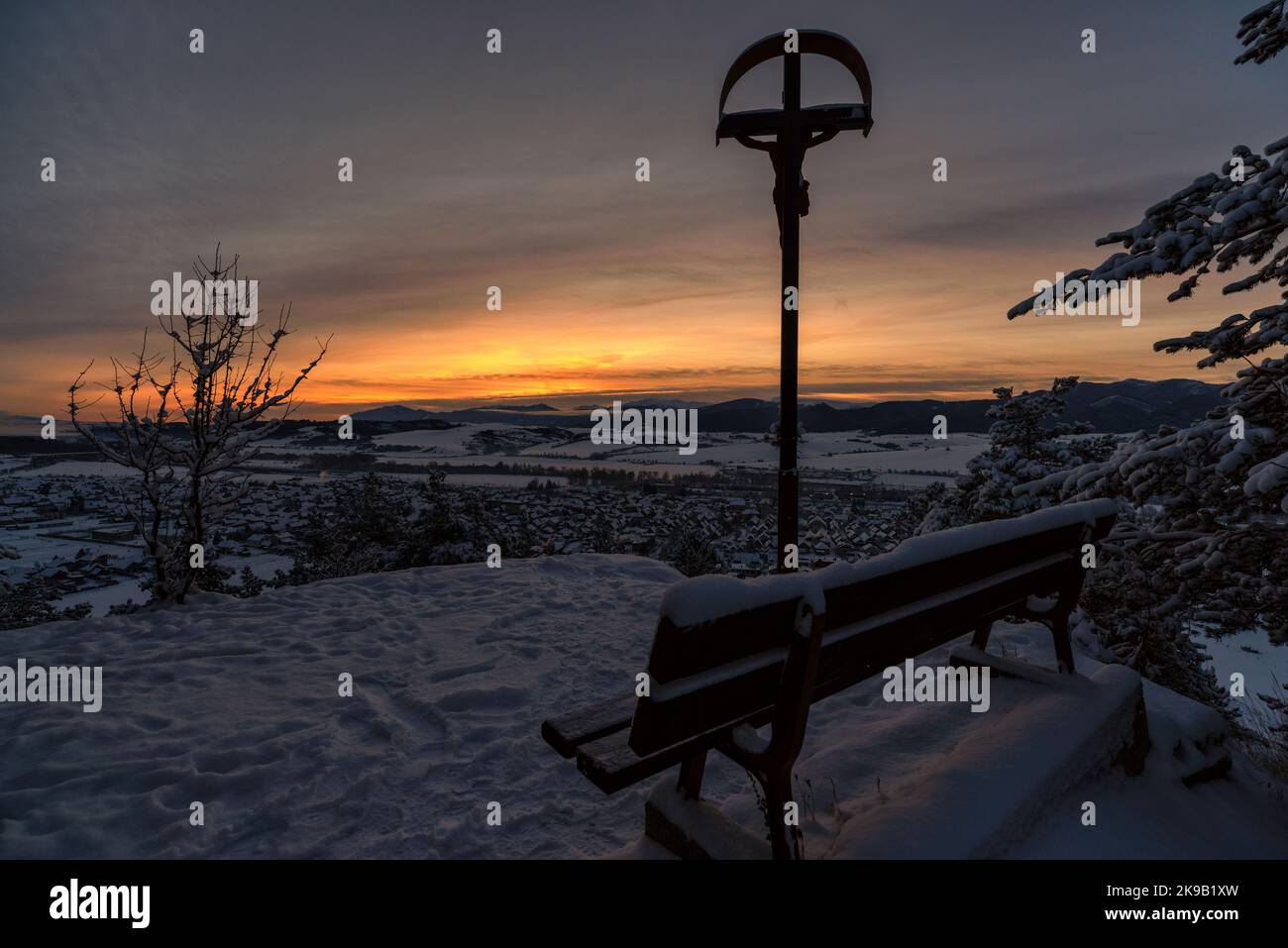 Empty lonely bench and cross with Jesus Christ in cold snowy winter ...