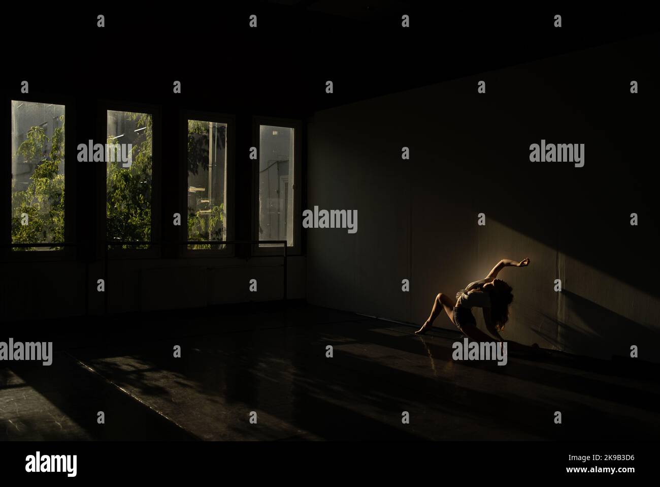 Dancer practicing in a dancing room alone with golden lights and ...