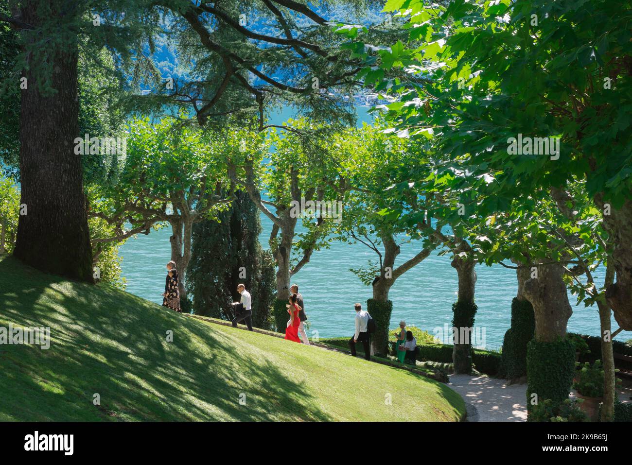 Lake Como garden, view in summer of people walking the lakeside path in ...