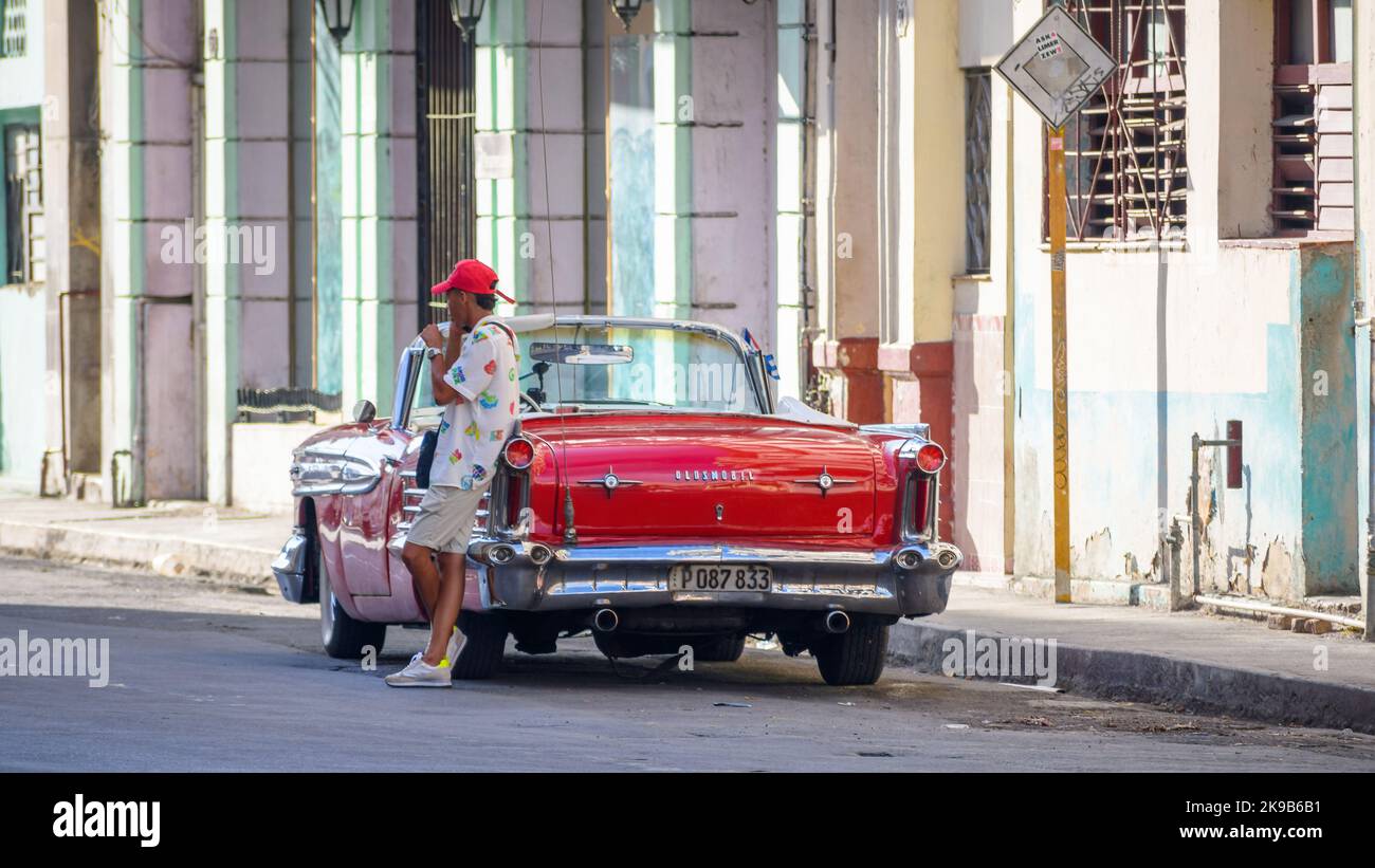 A young man, driver of a vintage convertible taxi, waits for costumers ...