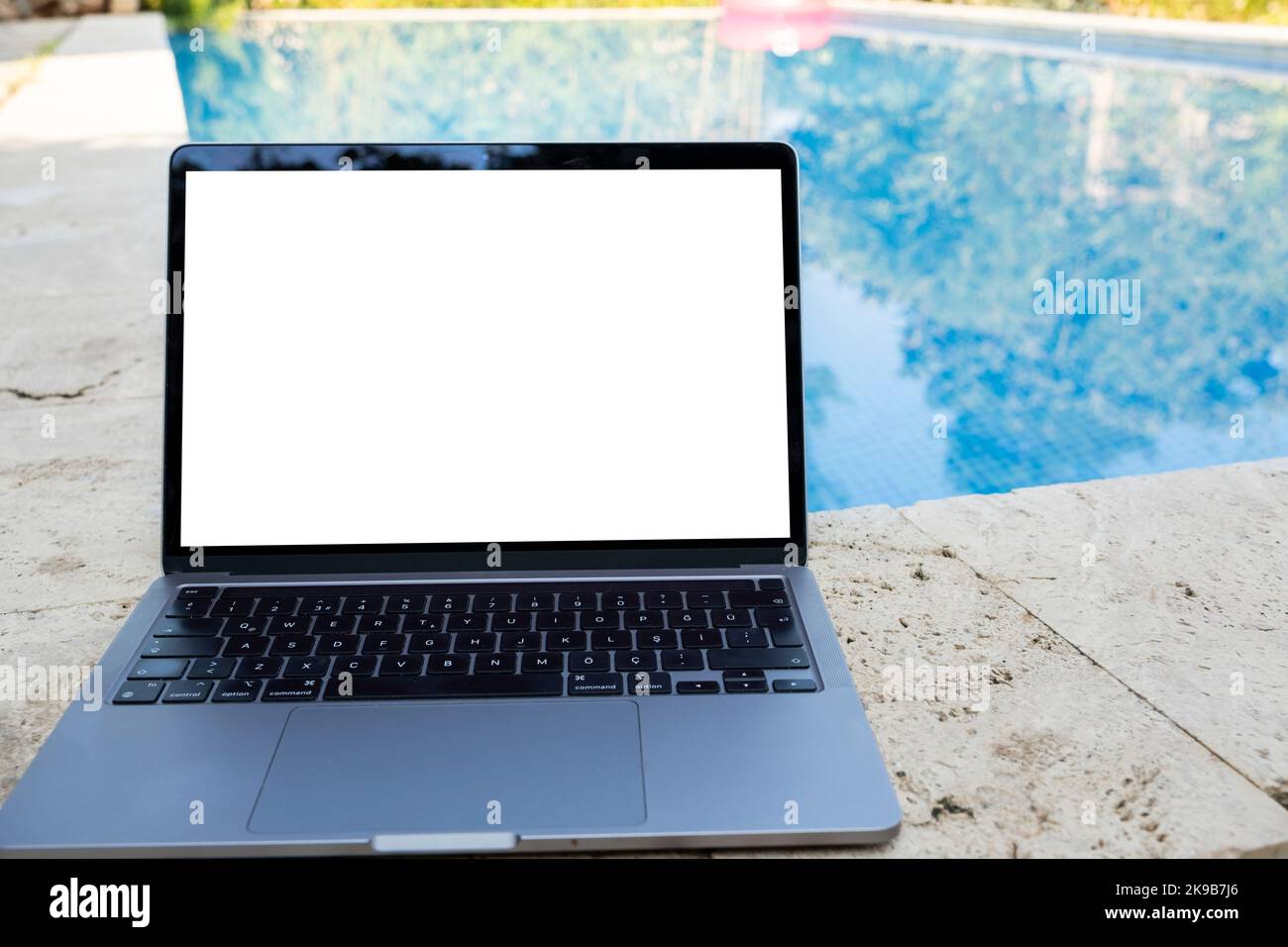 Laptop mock up, white blank display of modern laptop mock up. Notebook near swimming pool ...