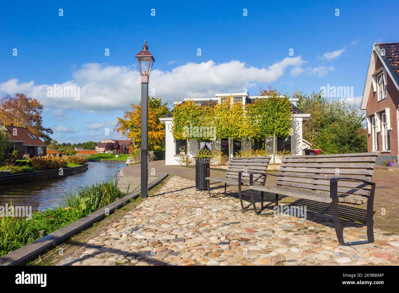 Wooden benches at the canal in historic village Kollum, Netherlands ...
