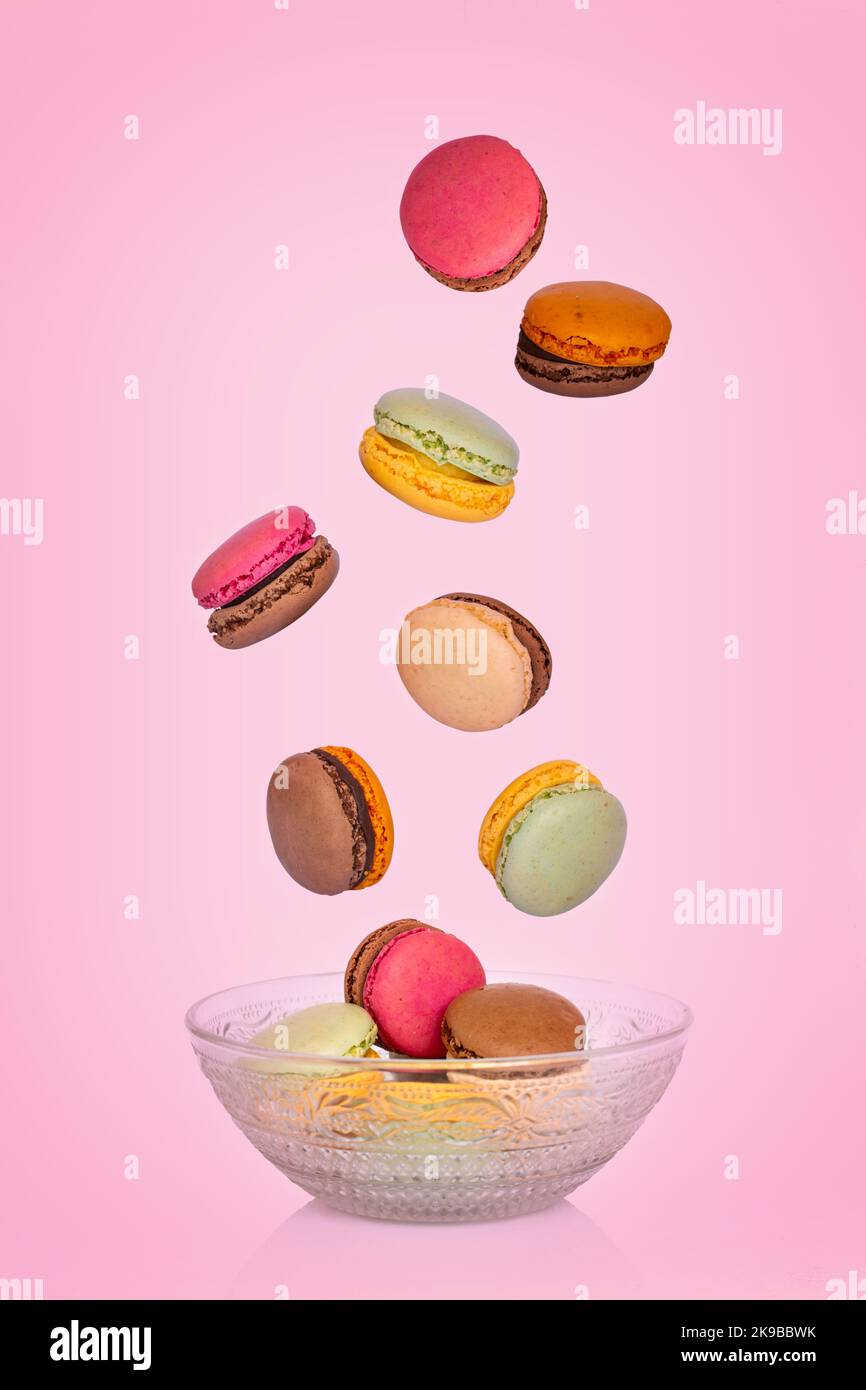 Flying macarons falling in a vintage plate on pink background Stock ...