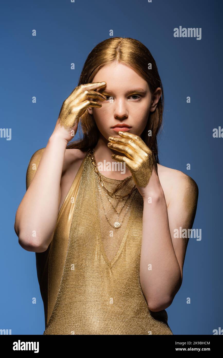 Stylish model in dress and hands in golden paint touching face isolated ...