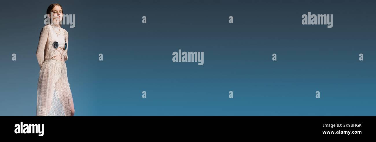 Stylish young model in fishnet skirt posing on gradient blue background ...