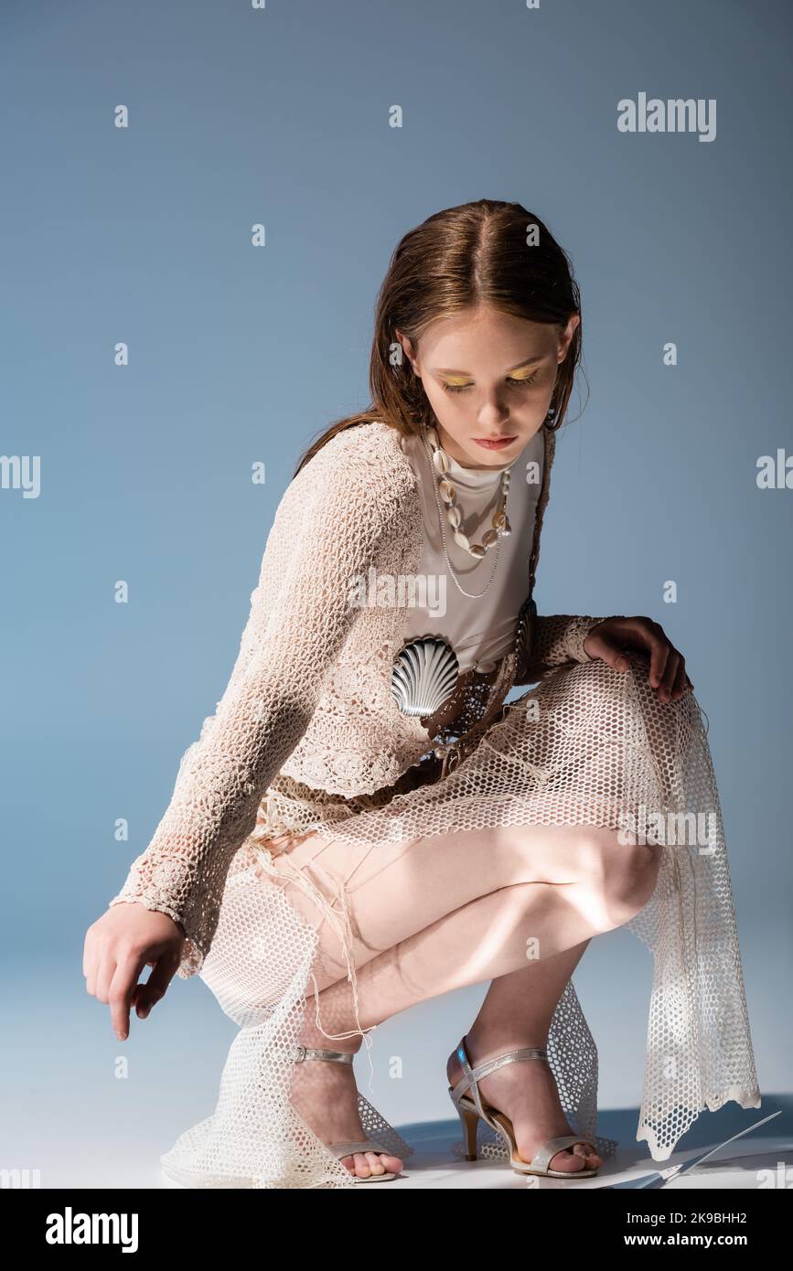 Young mermaid in knitted cardigan and fishnet skirt on gradient blue ...