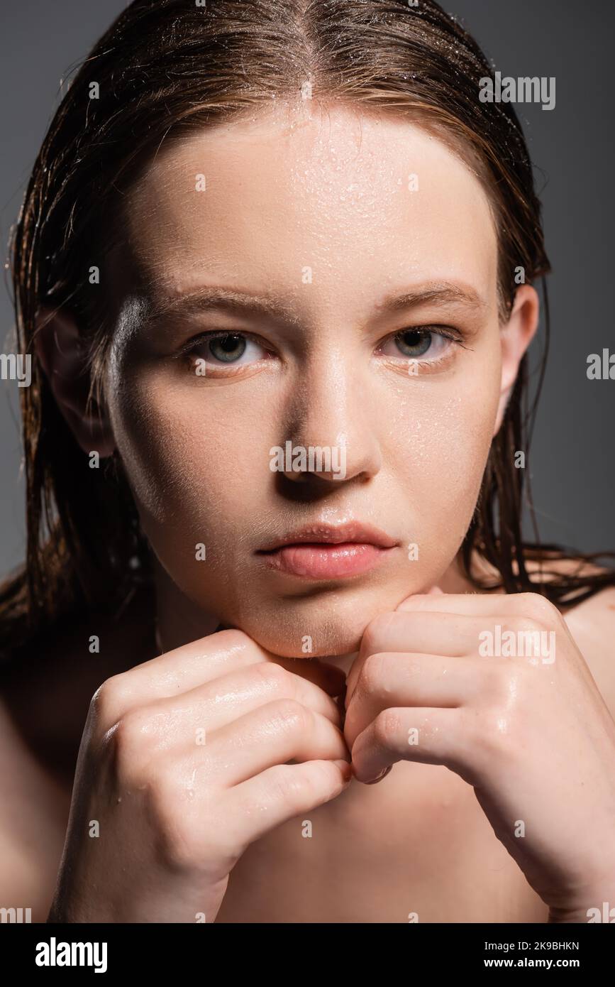 Portrait of pretty young woman with wet skin touching chin isolated on ...