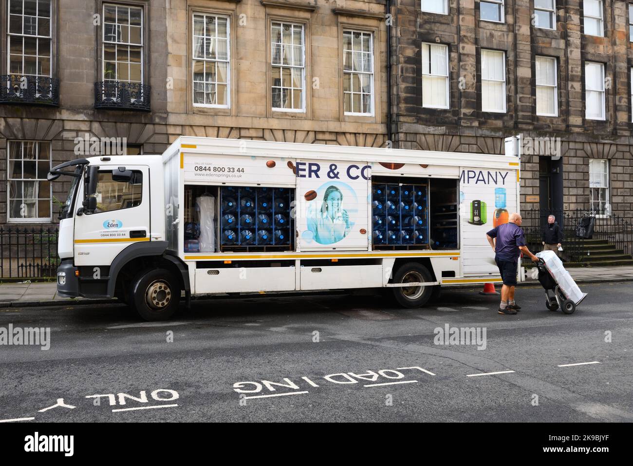 A van delivering containers of drinking water dispensers to offices in ...