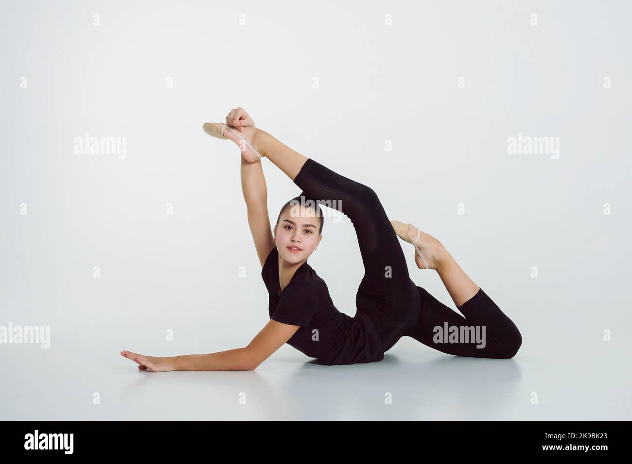 a girl from rhythmic gymnastics in a bodysuit shows stretching lying on ...