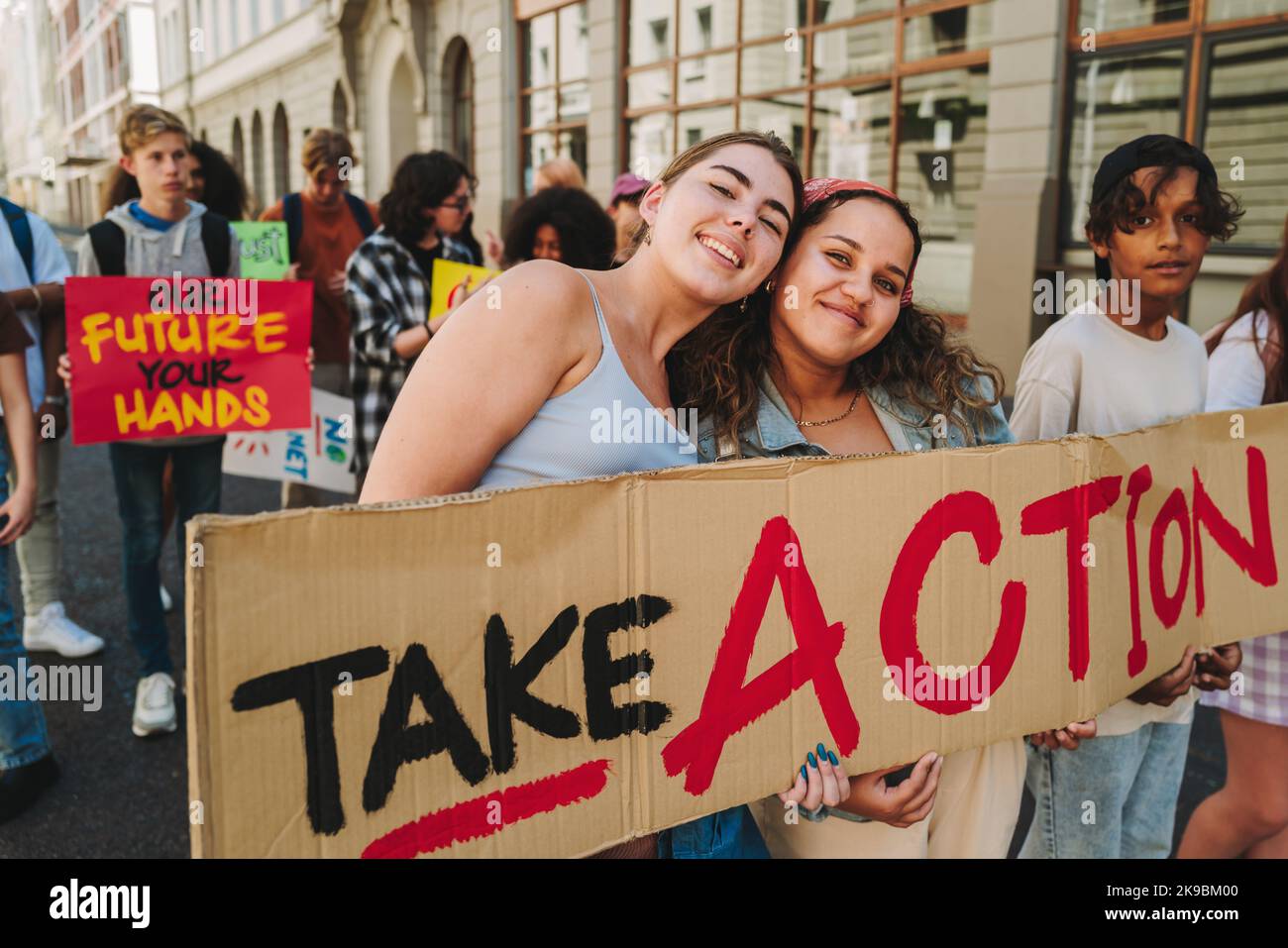 Happy teenage girls holding a banner at a climate change march. Group ...