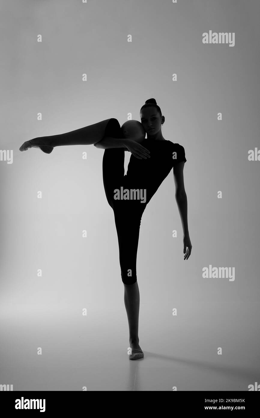 the silhouette of a rhythmic gymnastics girl in a bodysuit shows an ...