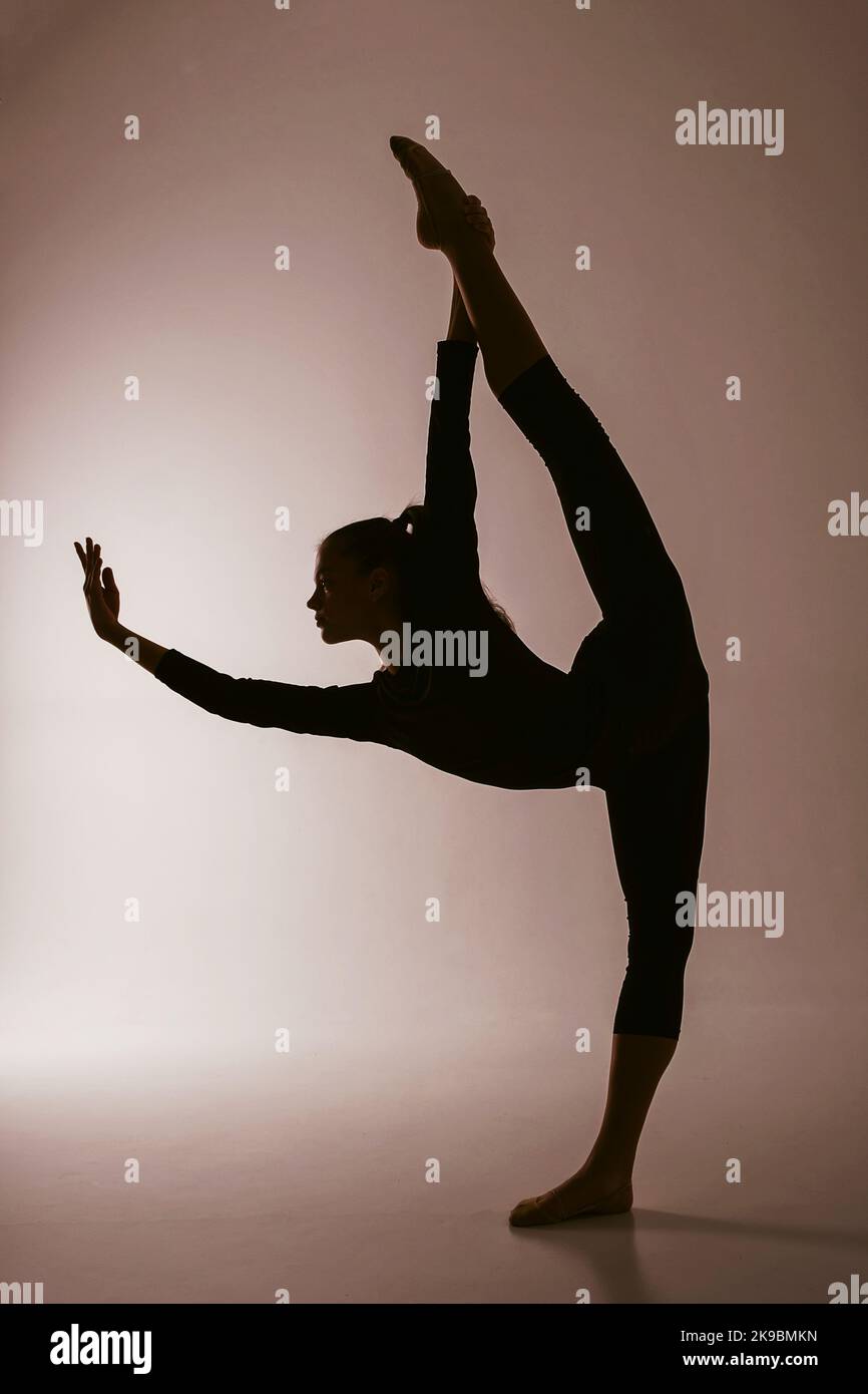 the silhouette of a rhythmic gymnastics girl in a bodysuit shows an ...