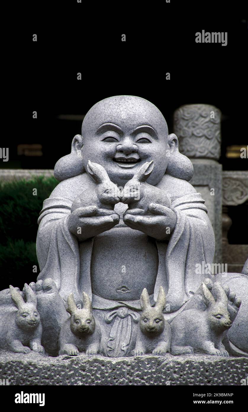 Buddhist monk rock statue standing, holding rabbits also surrounded by ...